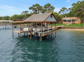 Um imóvel à beira-mar com um cais, um barco-de-teto e a casa principal.