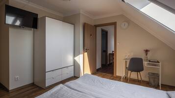 Quarto com cama, guarda-roupa, escrivaninha, cadeira e clarabóia.