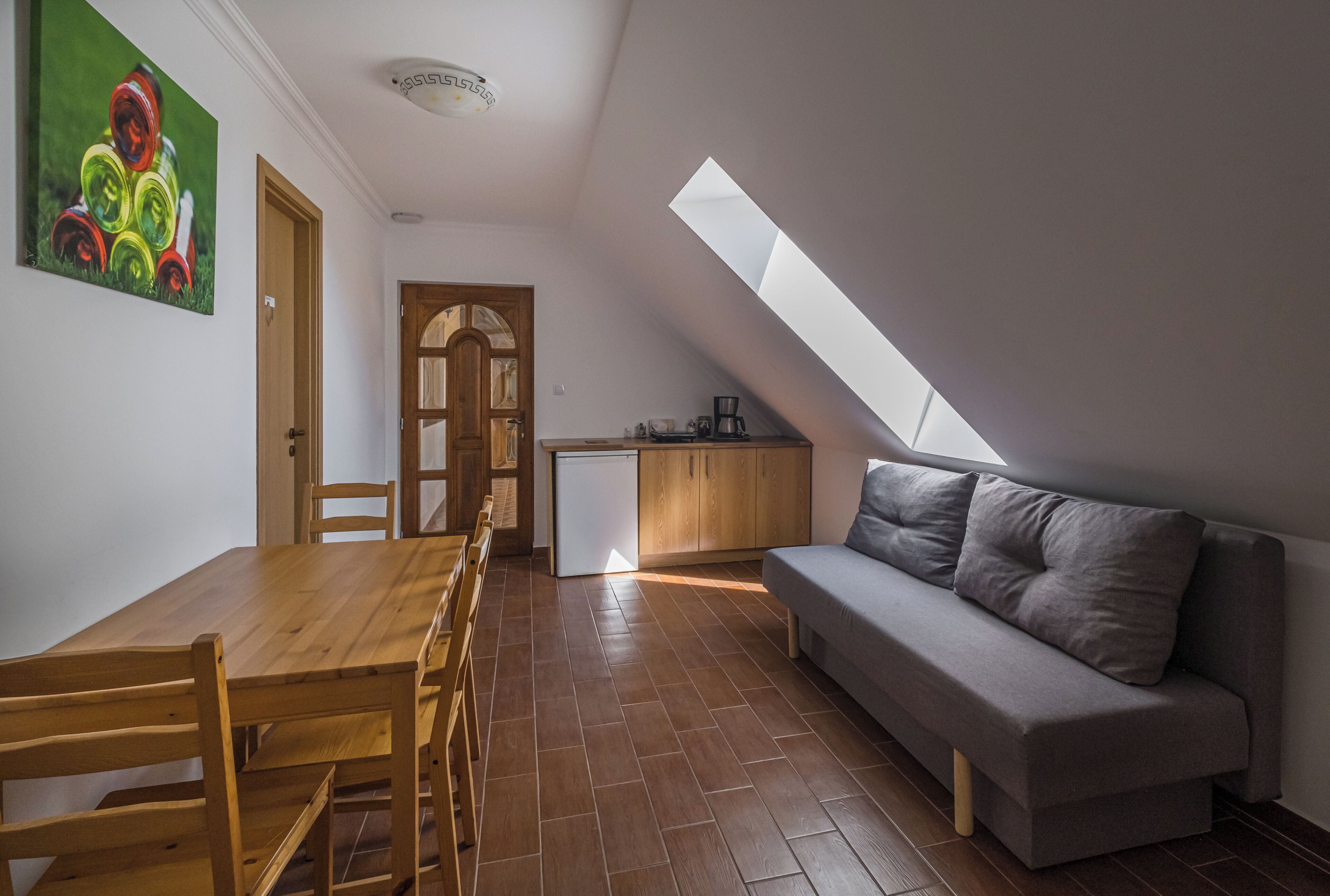 Um apartamento moderno estilo loft, com área de jantar, cozinha compacta e um quarto no mezanino com claraboia.