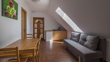 Um apartamento moderno estilo loft, com área de jantar, cozinha compacta e um quarto no mezanino com claraboia.