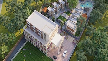 Um complexo hoteleiro moderno com vários edifícios, piscina e jardins bem cuidados.