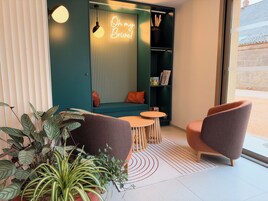 Um espaço de estar aconchegante, com uma luminária de neon, uma estante de livros e vista para a janela.