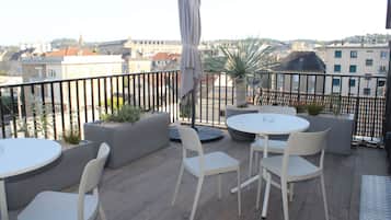 Terraço com mesa redonda e cadeiras, um vaso de planta e vista para a cidade.