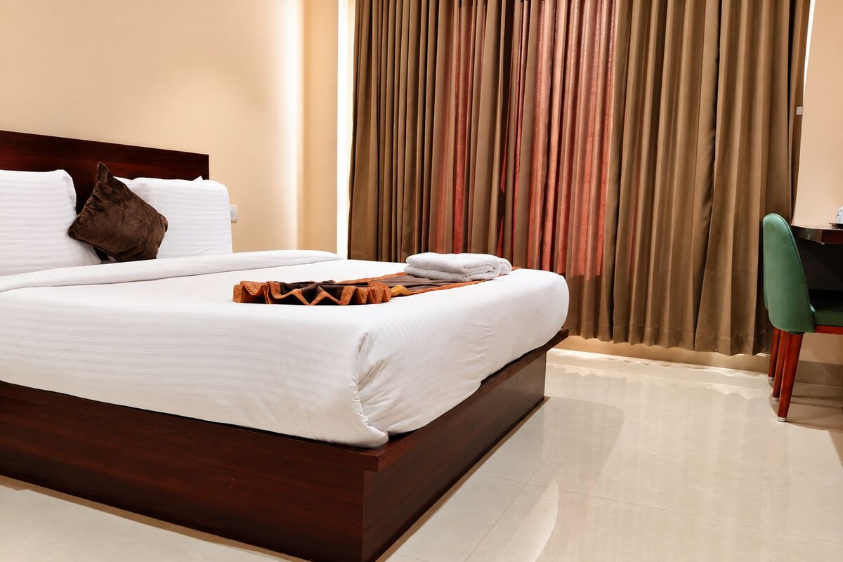 Quarto de hotel com uma cama grande, uma escrivaninha e uma cadeira.