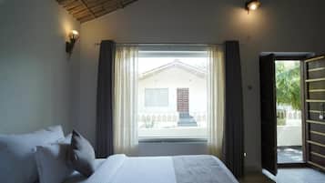 Quarto com cama, cortinas, janela e vista para um edifício.