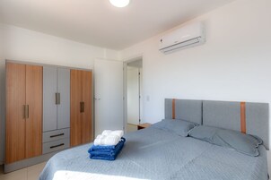 Quarto com cama, guarda-roupa e ar condicionado.