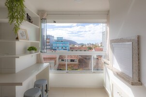 Uma varanda com vista para edifícios, uma planta e um quadro emoldurado.
