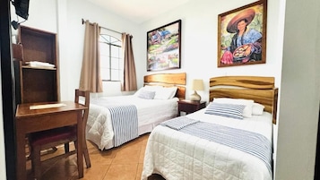 Quarto de hotel com duas camas, uma escrivaninha e uma cadeira.