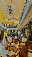 Um hall espaçoso com teto alto, uma escadaria e um espaço de estar com cadeiras de vime.