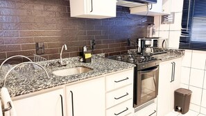 Cozinha com bancada de granito, eletrodomésticos de aço inoxidável e armários brancos.