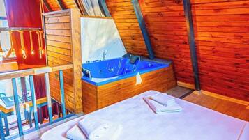 Um quarto com teto inclinado, uma cama, uma escrivaninha de madeira e uma banheira azul.