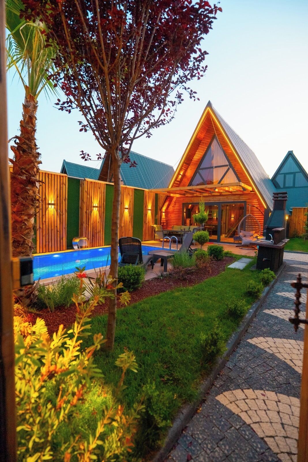 A modern lodge with a swimming pool, outdoor seating, and a well-maintained garden.