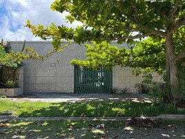 Um edifício com portão verde, área gramada e uma árvore.