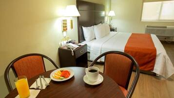 Quarto de hotel com cama, mesas de cabeceira, mesa de jantar com café da manhã e uma janela.