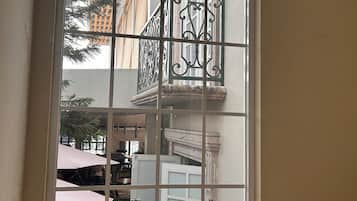 Uma janela com grade de metal decorativa, vista de um edifício com varandas e chão de azulejos.