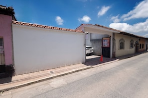 Um edifício com telhado telhado, fachada branca e um letreiro indicando tarifas de estacionamento.