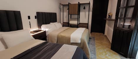 Quarto de hotel com duas camas, uma mesinha de cabeceira, um guarda-roupa e uma porta com painéis de vidro.