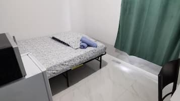Um quarto pequeno e limpo, com uma cama, uma escrivaninha e uma cadeira.
