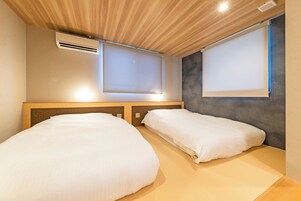 Quarto de hotel com duas camas, teto de madeira e janela com vista.