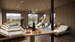 Um interior moderno com teto de madeira, janelas amplas e uma área de estar com sofás e uma mesa com petiscos.