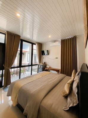 Quarto de hotel com cama grande, televisão, aparelho de ar condicionado e varanda com vista.