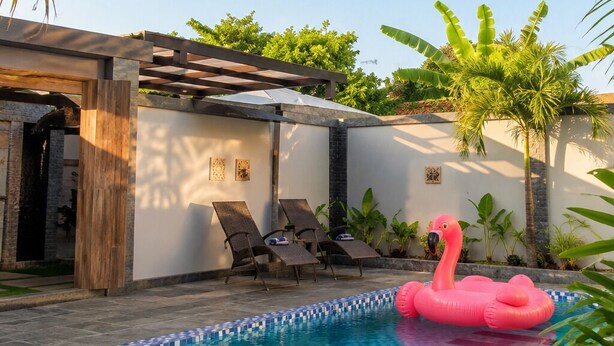 Uma piscina com um flutuador em formato de flamingo rosa, rodeada por espreguiçadeiras e um pérgula.