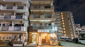Um edifício com vários andares, varandas, entrada no nível da rua e uma placa.