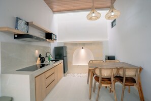 Uma cozinha moderna com área de jantar, armários de madeira, micro-ondas embutido e painel de fundo de pedra.