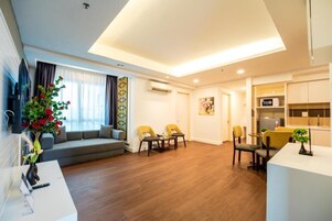 Uma sala de estar moderna com um sofá, cadeiras, uma mesa de centro e uma TV fixada na parede.