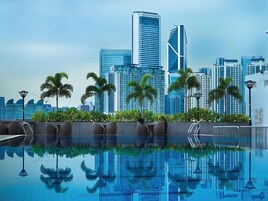 Paisagem urbana moderna com arranha-céus e uma piscina refletora.