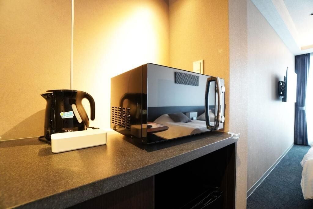 Quarto de hotel com área de cozinha compacta, incluindo cafeteira e micro-ondas.