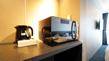Quarto de hotel com área de cozinha compacta, incluindo cafeteira e micro-ondas.