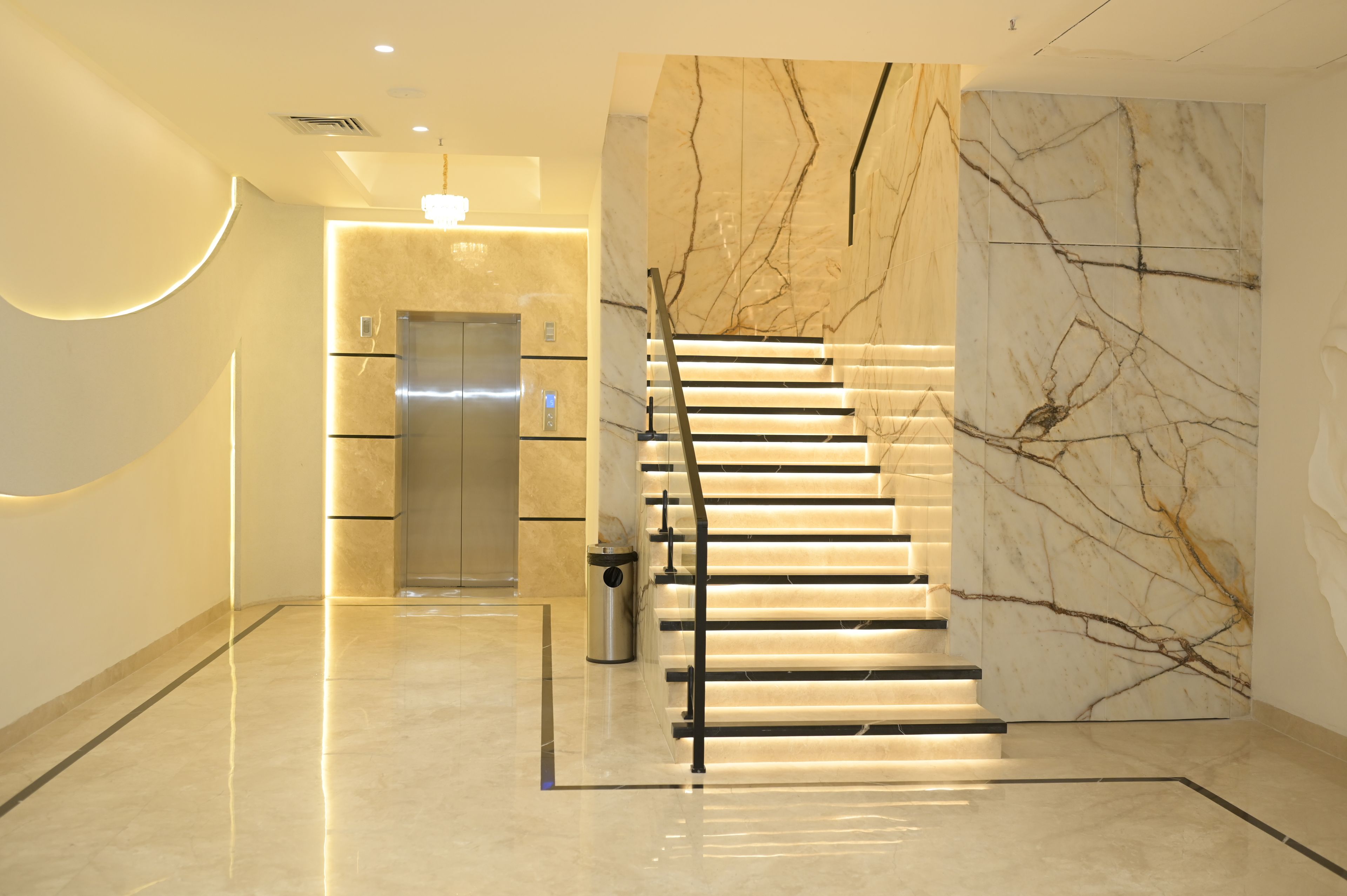 Um interior moderno com uma escadaria de mármore, elevador e design minimalista.