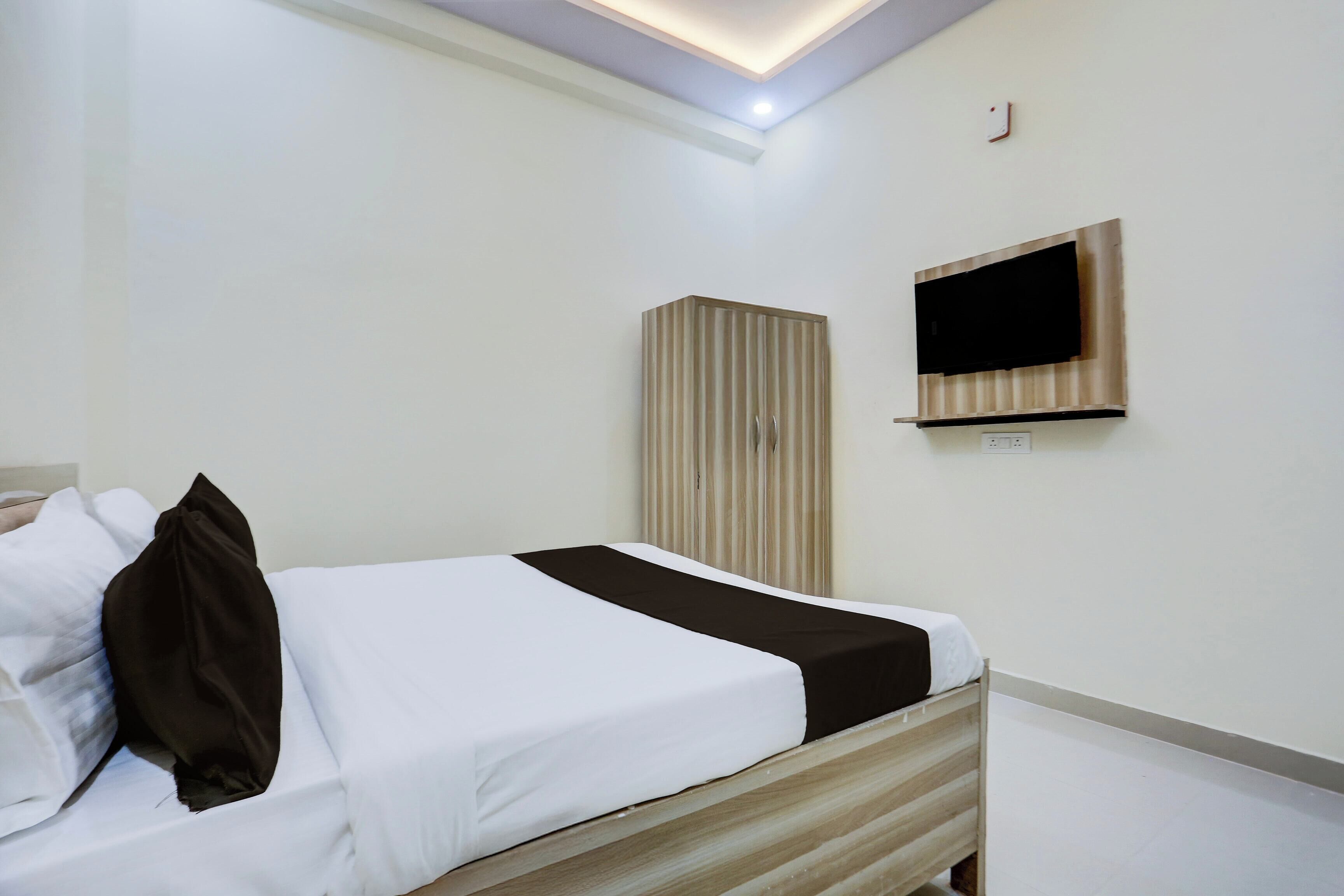 Quarto de hotel com cama, guarda-roupa, televisão e luz no teto.