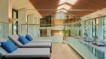 Um interior moderno com piscina de vidro, espreguiçadeiras e teto de madeira.