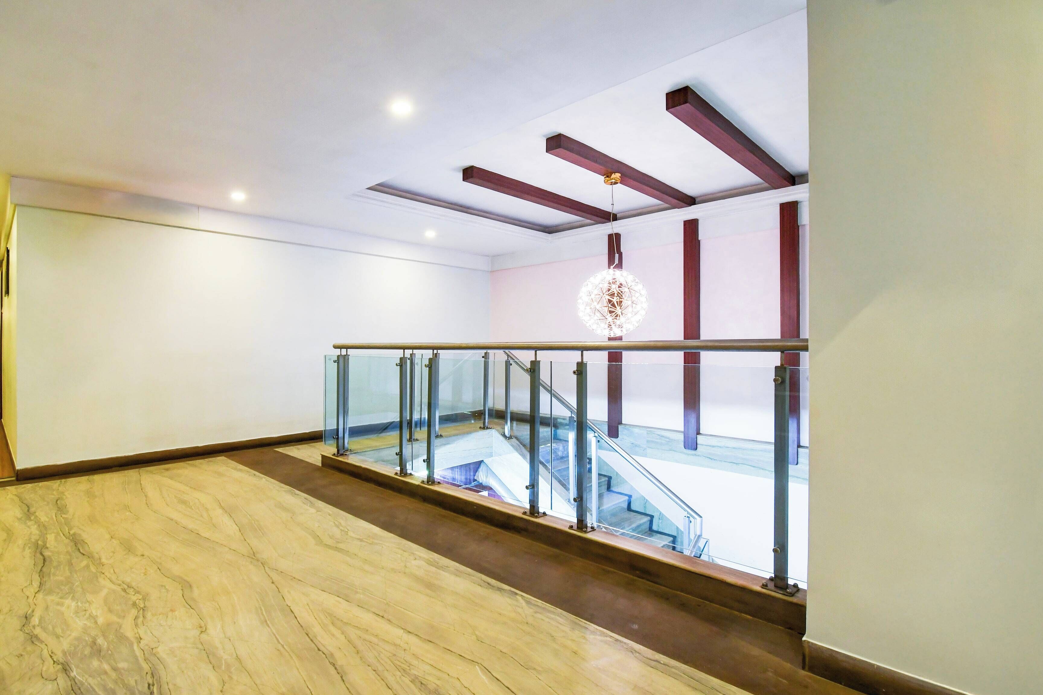 Um interior espaçoso com piso de mármore, guarda-corpo de vidro e escada que leva a uma área externa.
