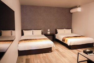 Quarto de hotel com duas camas, mesa de cabeceira e um aparelho de ar condicionado.