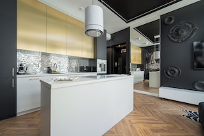 Cozinha moderna com ilha central, eletrodomésticos de aço inoxidável e esquema de cores preto e branco.