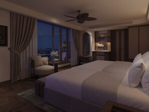 Quarto de hotel com uma cama grande, uma cadeira, uma mesa de cabeceira, um espelho e uma janela com cortinas.