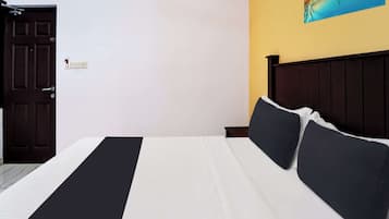 Quarto com cama, mesa de cabeceira, porta e interruptor de luz fixado na parede.