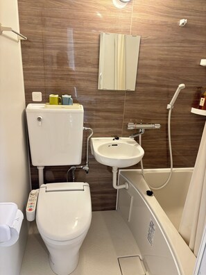 Casa de banho compacta com sanita, lavatório e chuveiro.