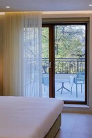 Quarto de hotel com uma cama, uma porta de vidro deslizante que dá para uma área externa com mesas e cadeiras.