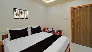 Quarto de hotel com uma cama, uma porta de madeira e uma pequena mesa com um tabuleiro.