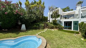 Uma casa moderna com piscina, rodeada por vegetação exuberante e palmeiras.