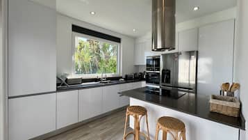 Uma cozinha moderna com uma ilha grande, eletrodomésticos de aço inoxidável e uma janela com vista para o verde.
