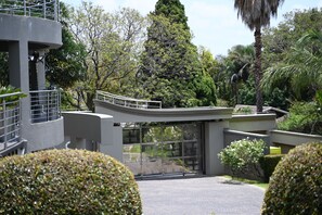 Um edifício moderno com telhado curvo, cercado por vegetação exuberante e árvores.