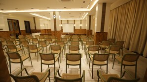 Uma sala de conferências com fileiras de cadeiras voltadas para um quadro branco, uma tela de projeção e uma parede revestida de madeira.