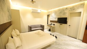 Um quarto com cama, uma cadeira, uma televisão e um guarda-roupa.