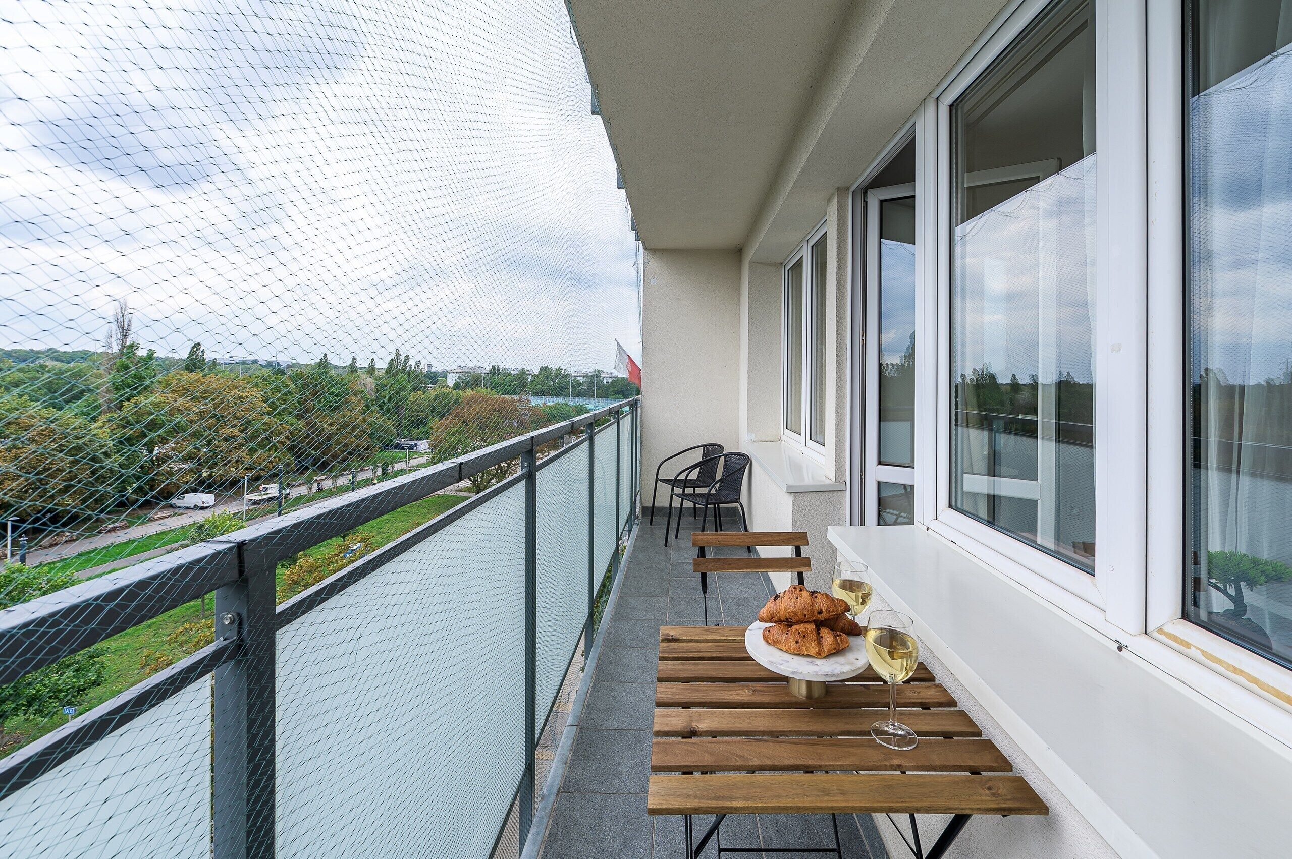 Uma varanda com vista para um jardim e uma mesa com comida e bebida.