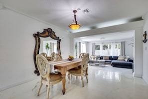 Uma sala de jantar com mesa e cadeiras de madeira, um espelho grande e um lustre.